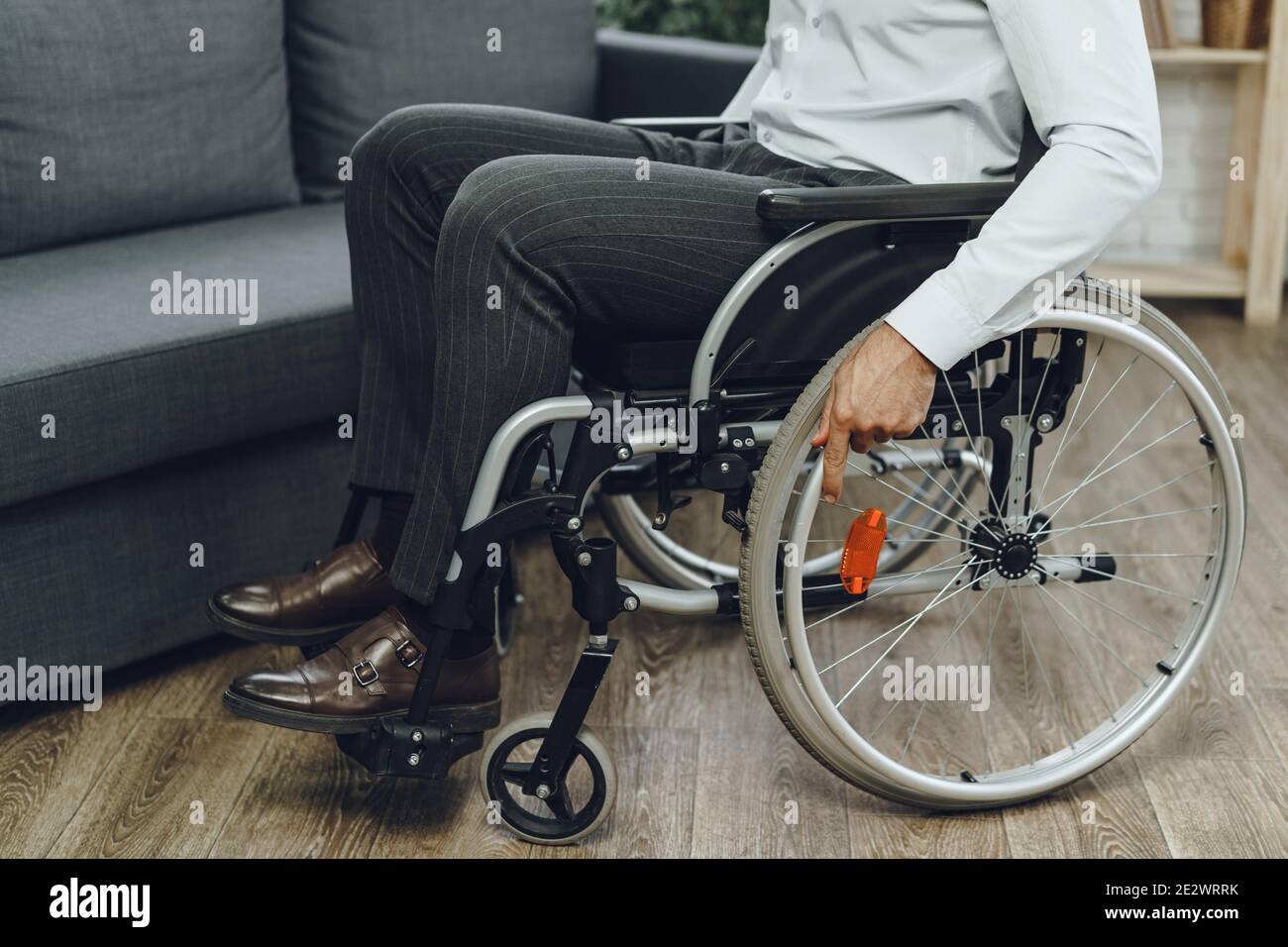 Disabled man tries to sit down on a sofa from wheelchair Stock Photo ...