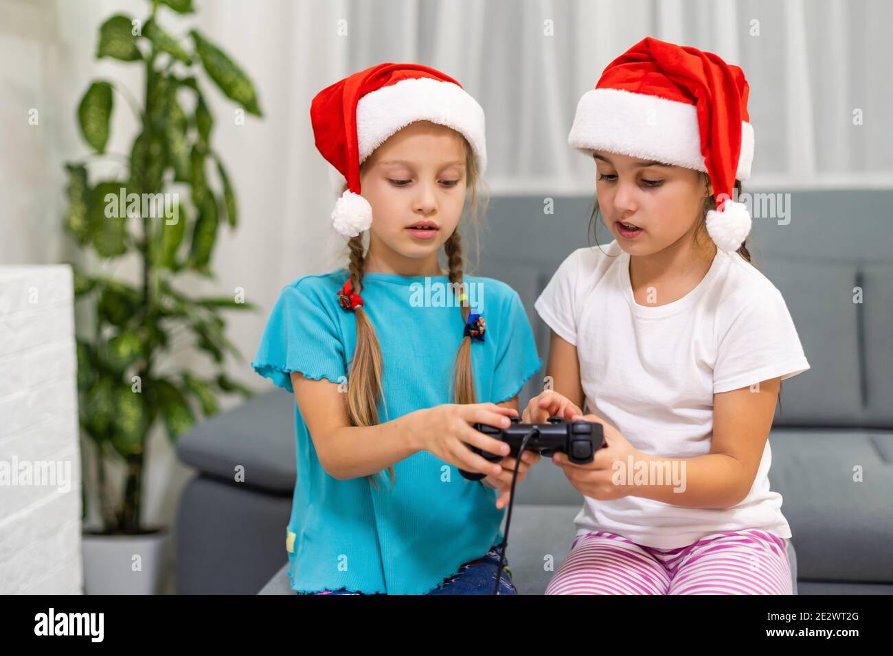 Two girls little sister play fun in a video game with a joystick in ...