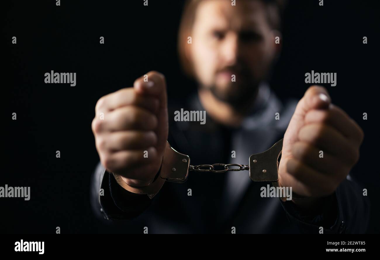 Man standing in handcuffs over black background Stock Photo - Alamy