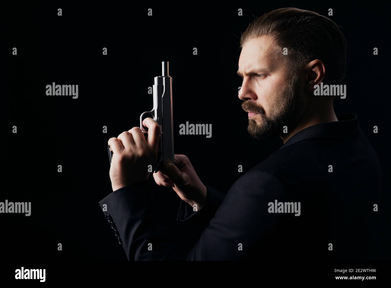 Brutal killer overcharging gun in studio Stock Photo - Alamy