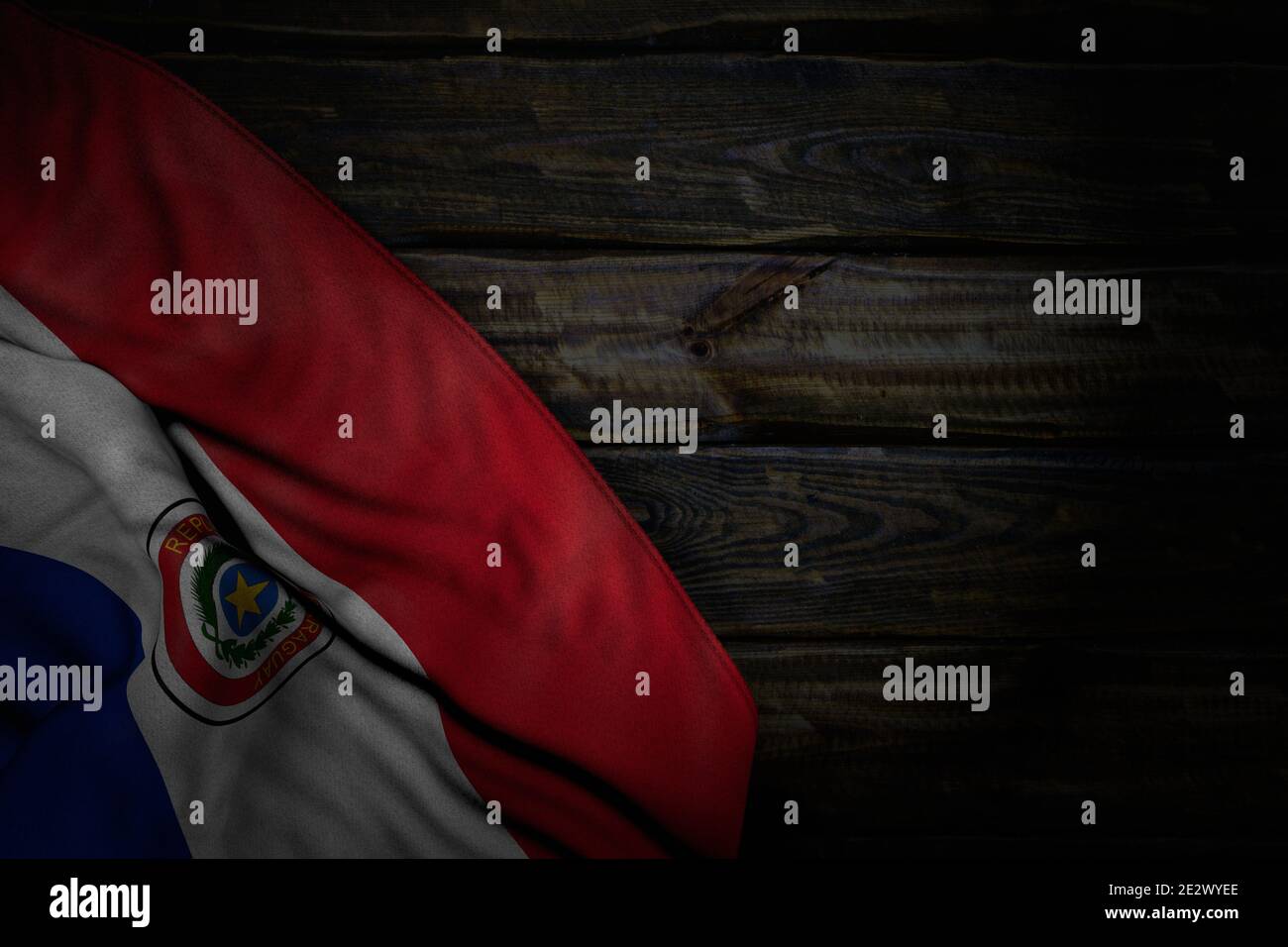 beautiful dark photo of Paraguay flag with big folds on old wood with ...