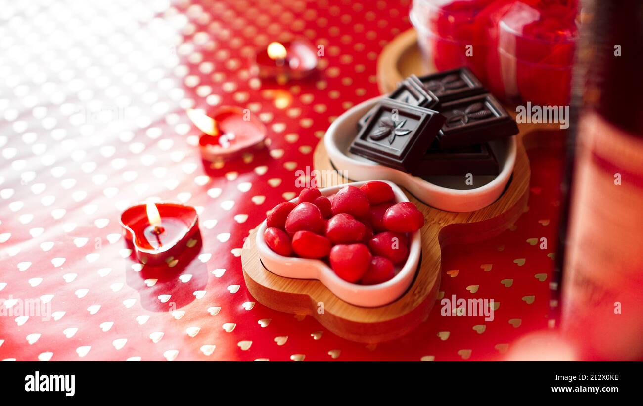 Chocolates and sweets on heart-shaped plates. Festive table setting for ...