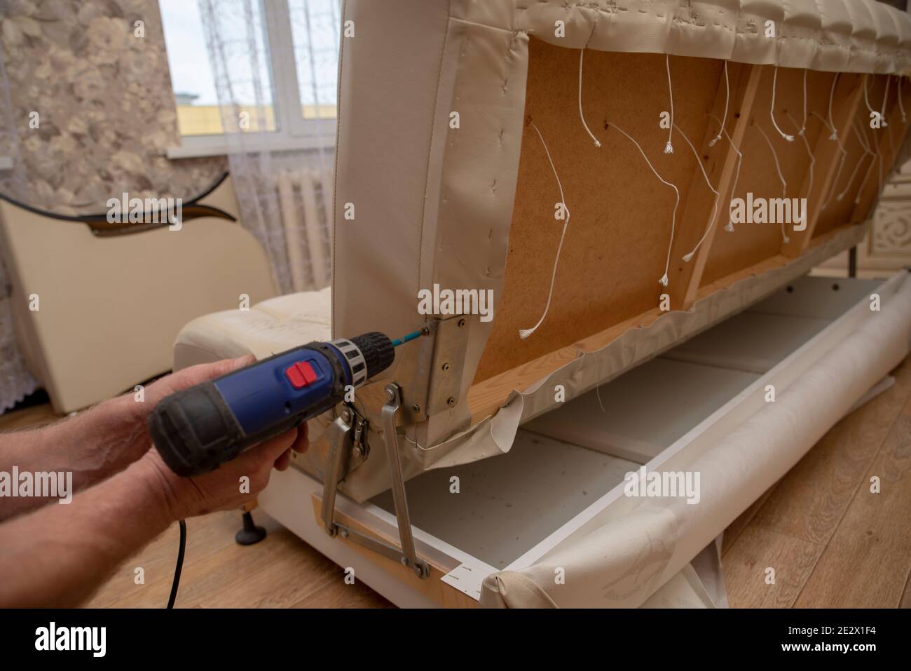 Repair the sofa. Diy. Unscrews the screw with a screwdriver Stock Photo ...