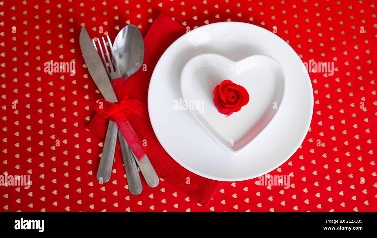 Romantic decoration of holiday table. White plates in the shape of a ...