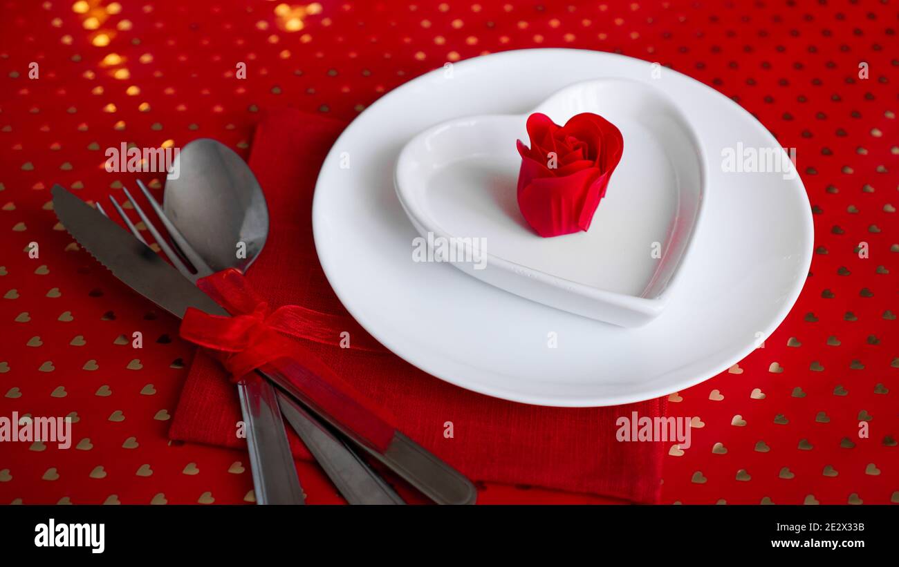 Romantic decoration of holiday table. White plates in the shape of a ...