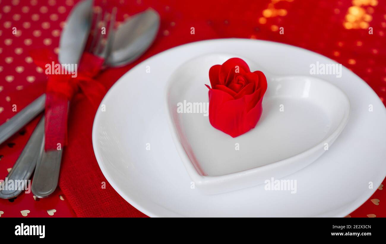 Romantic decoration of holiday table. White plates in the shape of a ...