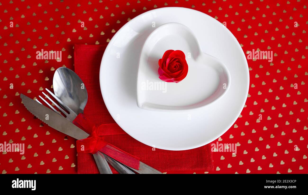 Romantic decoration of holiday table. White plates in the shape of a ...