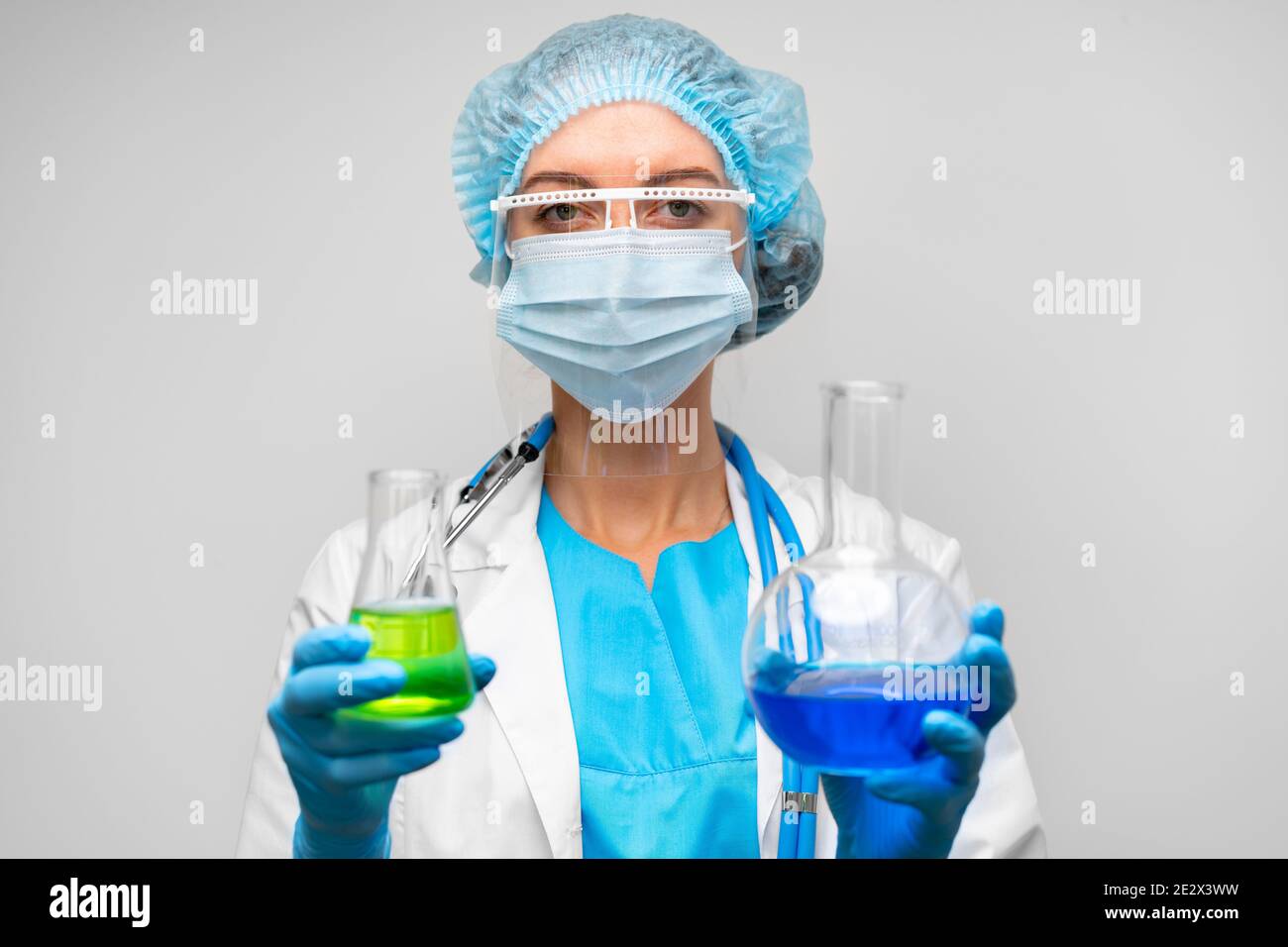Woman scientist holding laboratory flask with chemical liquid, gray ...