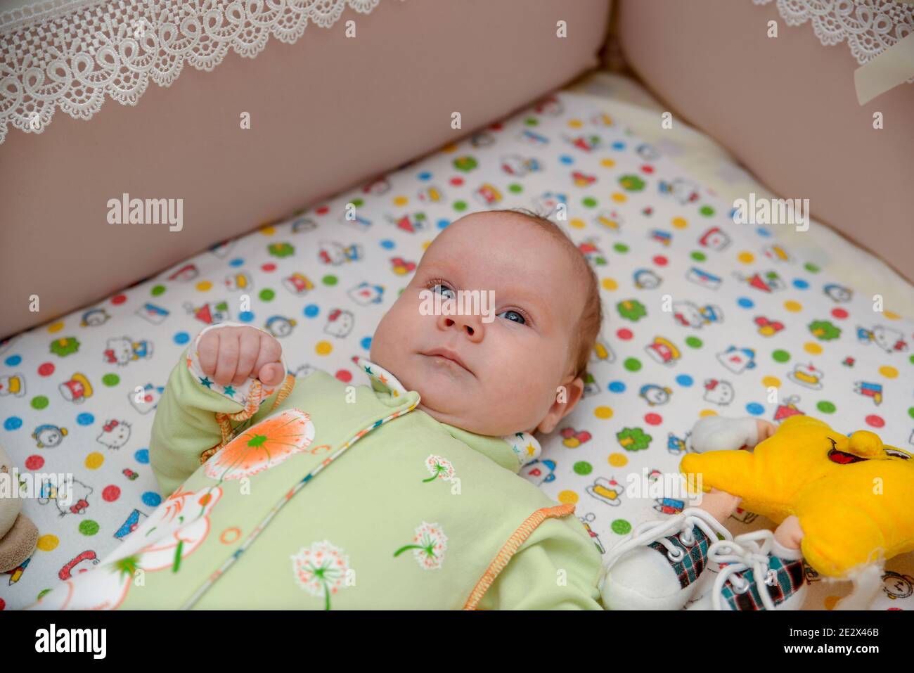 A small child lies in a cot with toys Stock Photo - Alamy