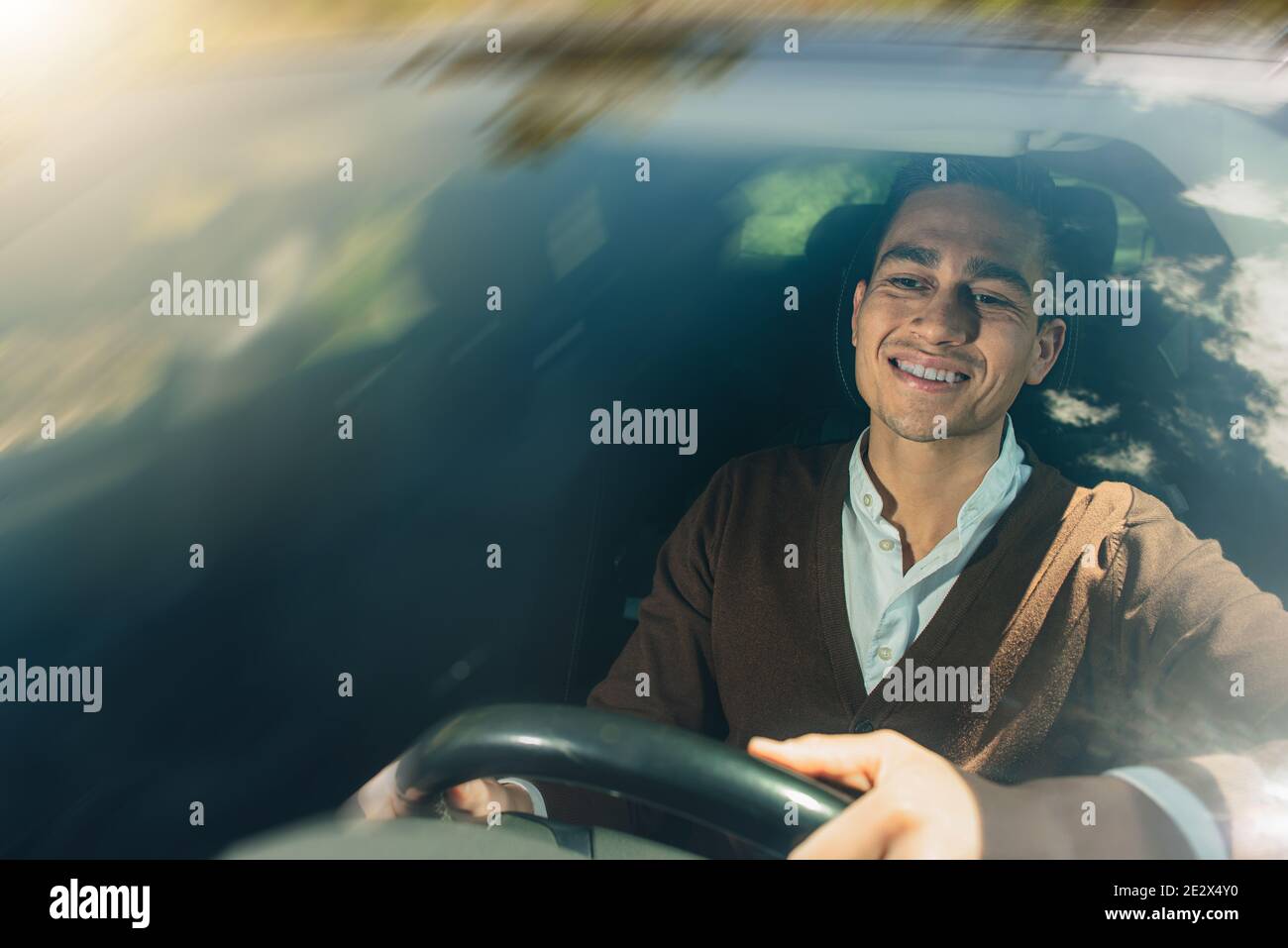 Latin man happily smiling and driving a car Stock Photo - Alamy
