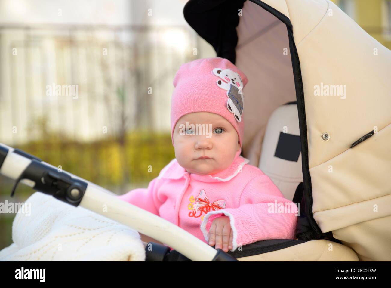 A child in a stroller on a walk in the fall. Heat dressed in a pink ...