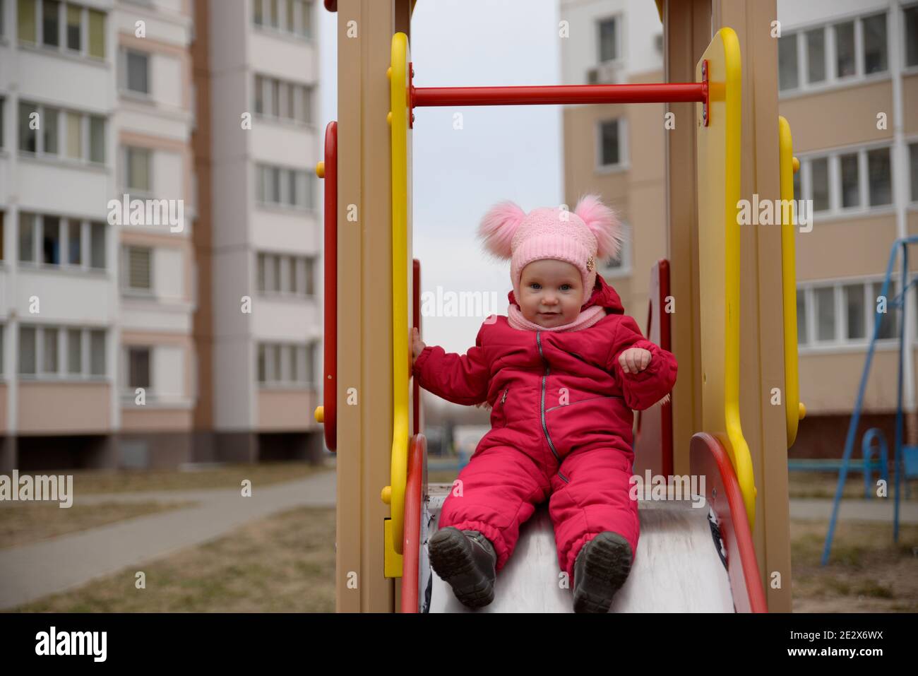 A child rides a children's slide in the yard near the house. Playground ...