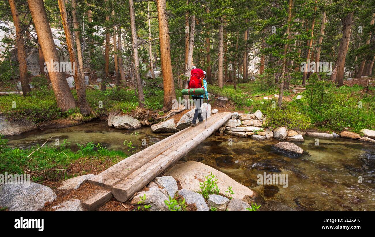 Backpacker crossing creek in the John Muir Wilderness, Sierra Nevada ...