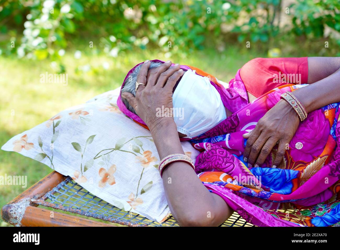 Old lying Indian woman in a face mask suffering from a terrible ...