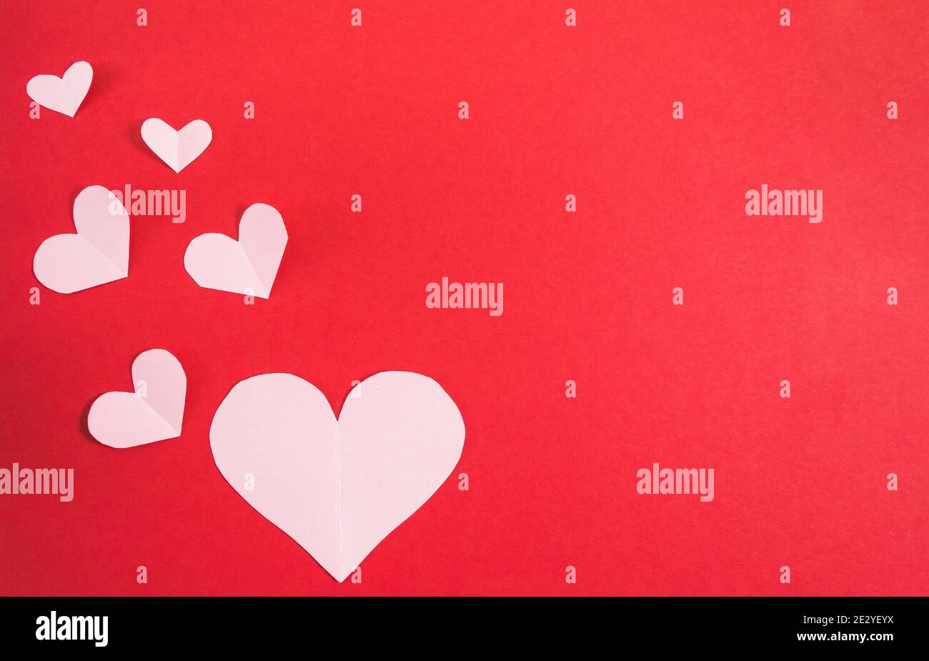 Paper hearts of different sizes on a red background. Abstract ...