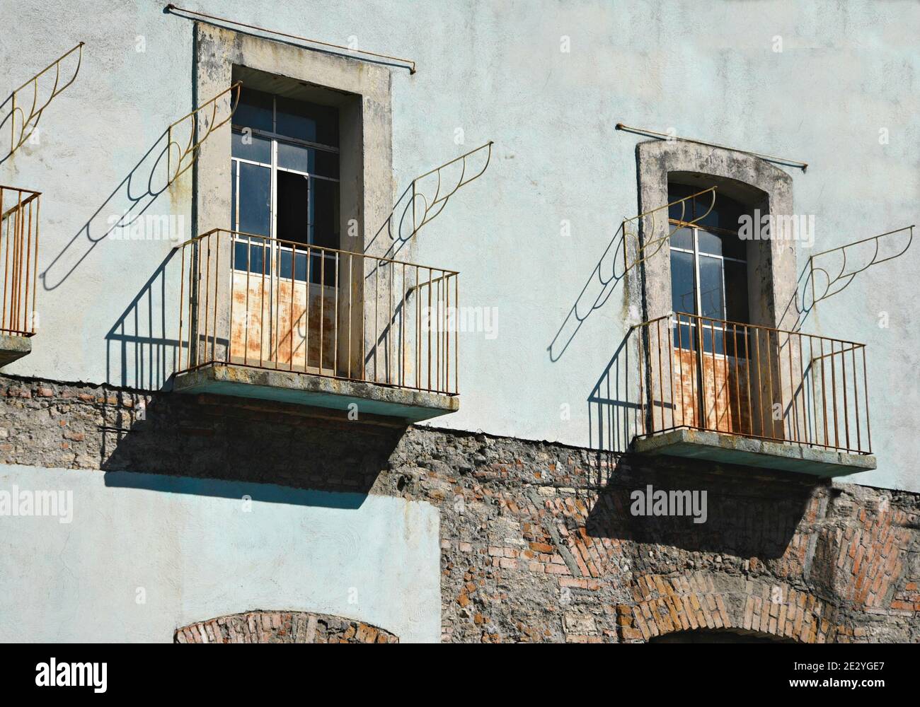 Colonial house facade with a grey stucco wall and handcrafted iron ...