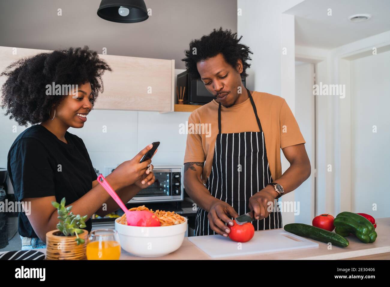 Afro couple cooking together in the kitchen Stock Photo - Alamy