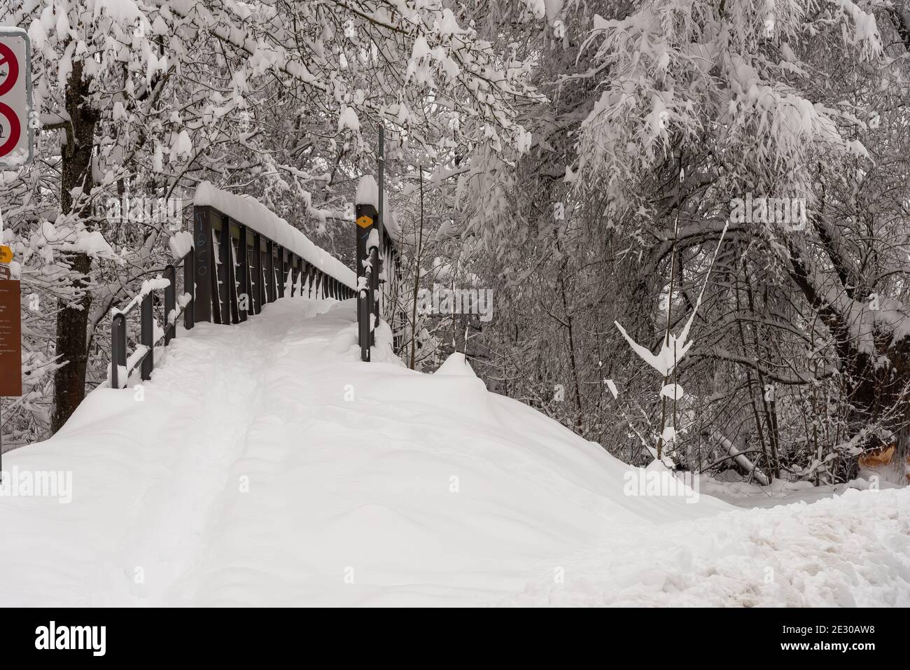 Snow covered pedestrian bridge over river after heavy snowfall Stock ...