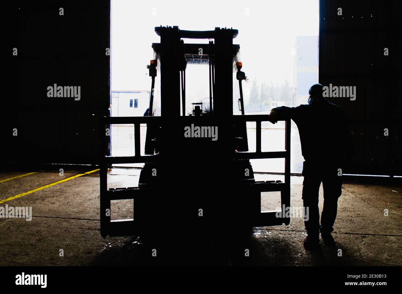 Tired operator rests after a days hard work. Leaning on a forklift ...