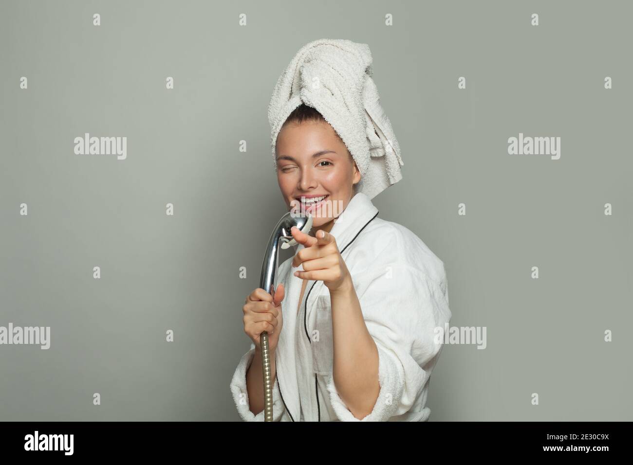 Young happy spa woman taking a shower and singing on white background ...