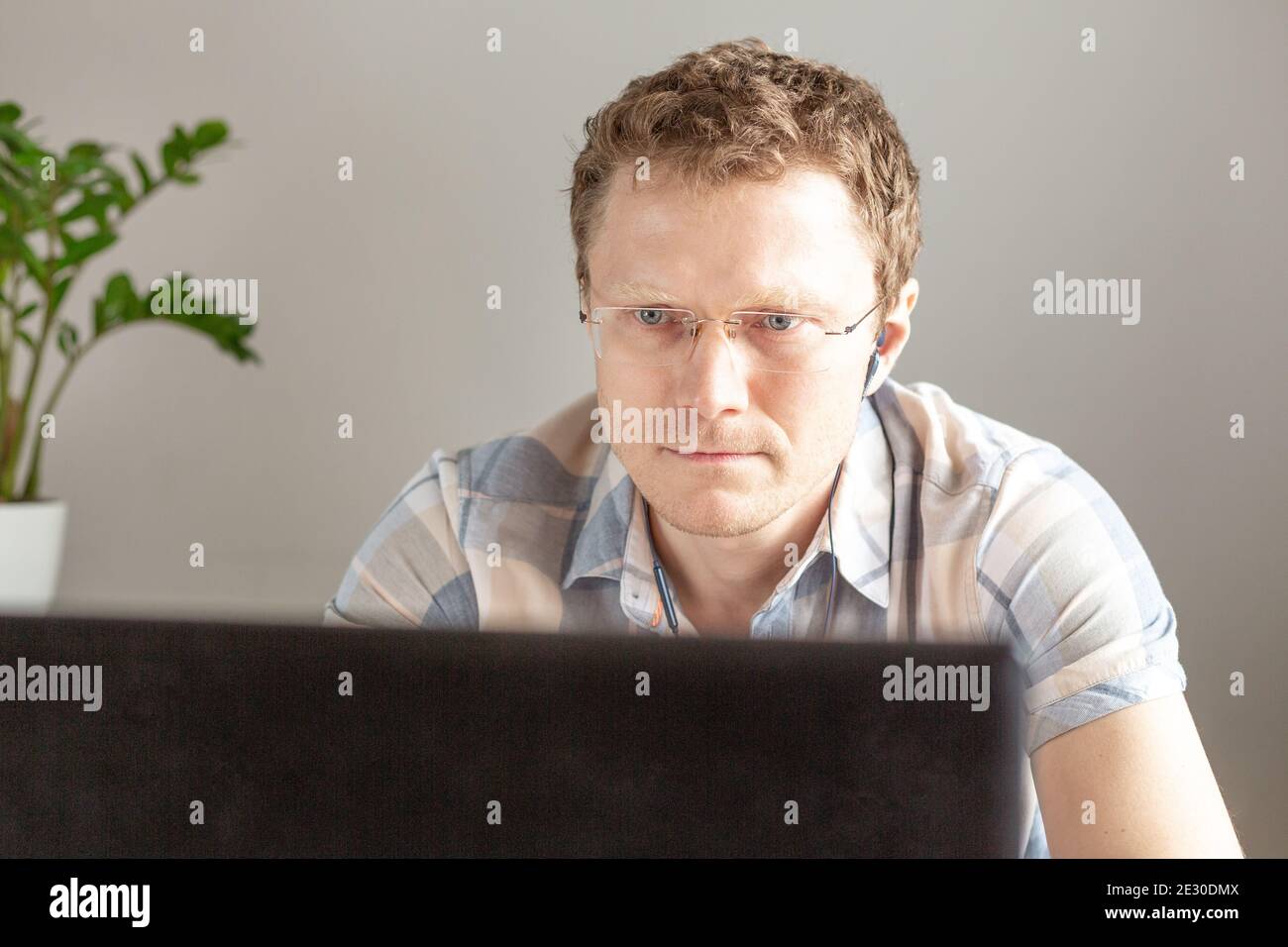 Programmer working from home, remote, home office. A man with glasses ...