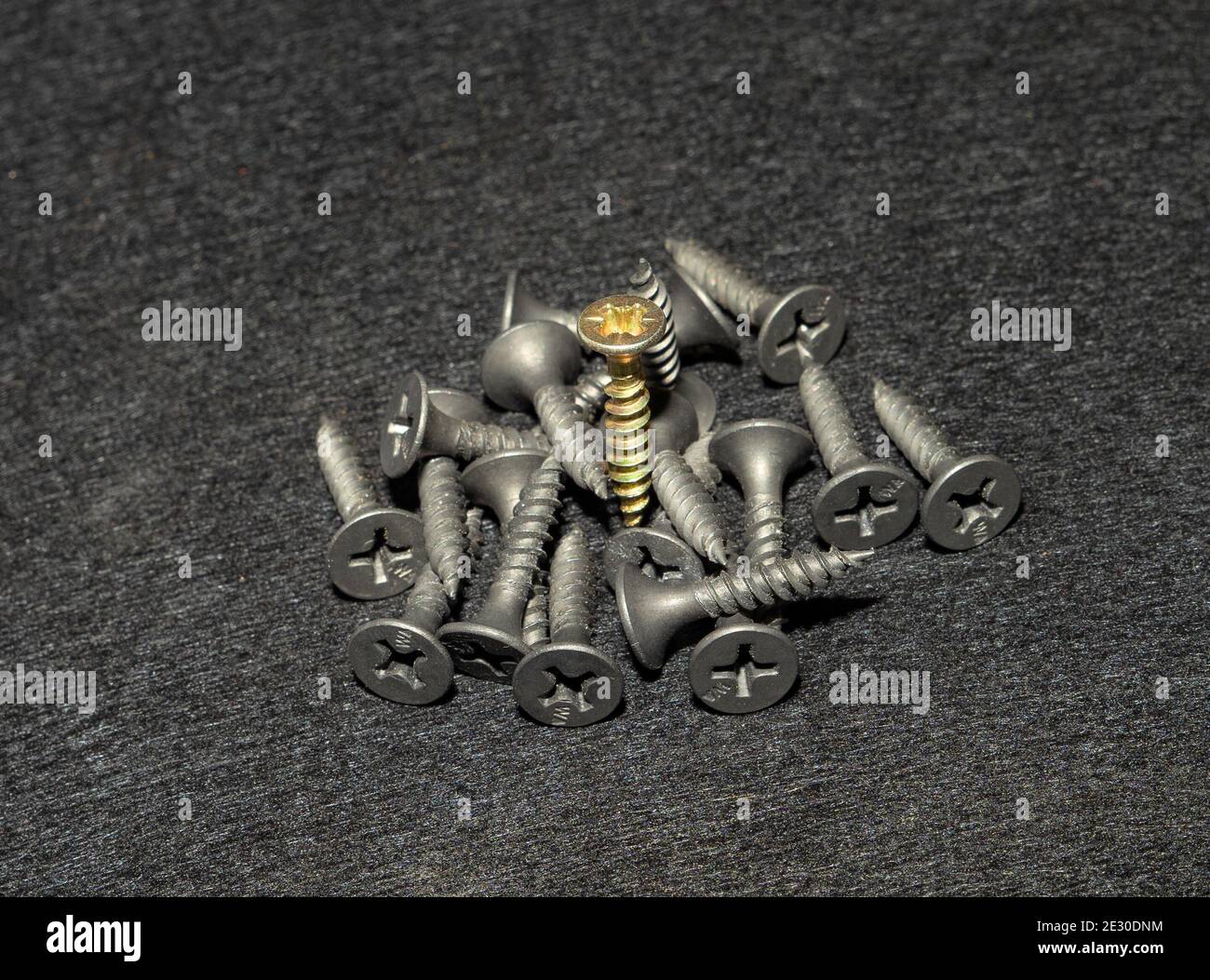 A bunch of black self-tapping screws with one gold self-tapping screw ...