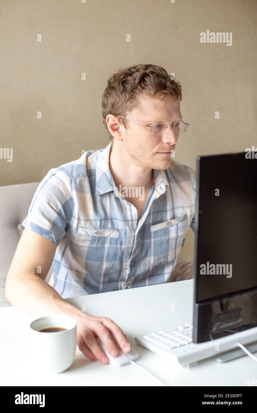 Programmer working from home, remote, home office. A man with glasses ...
