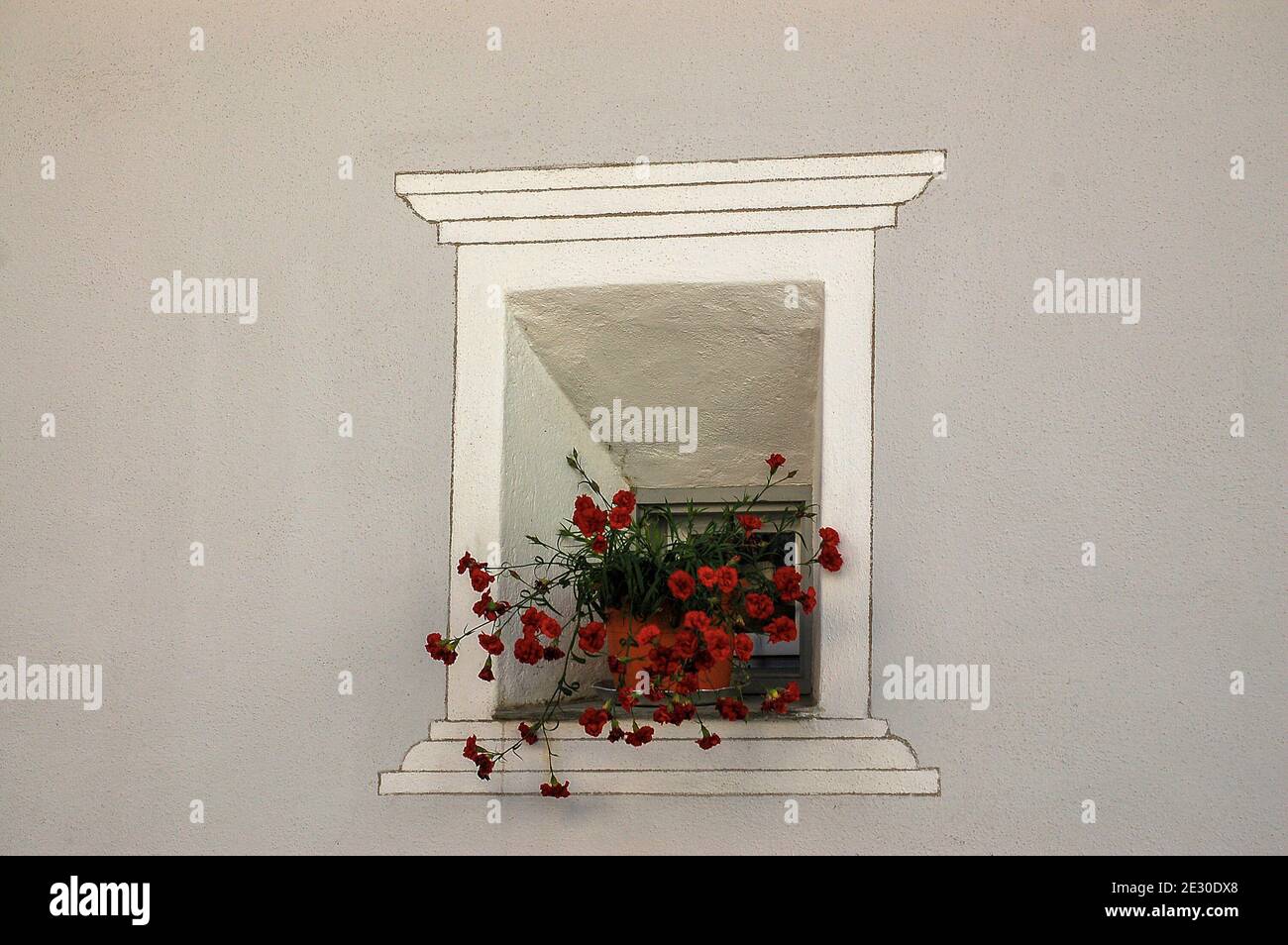 Old small window with red geraniums and geometric decorations on the ...