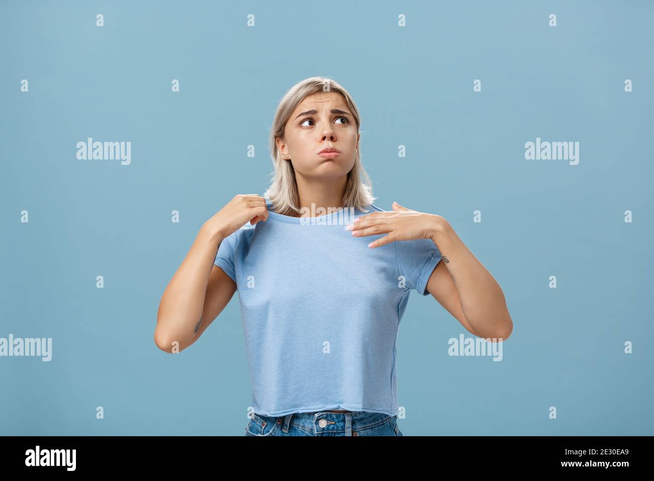 Girl feeling discomfort from heat standing over blue background in fug ...
