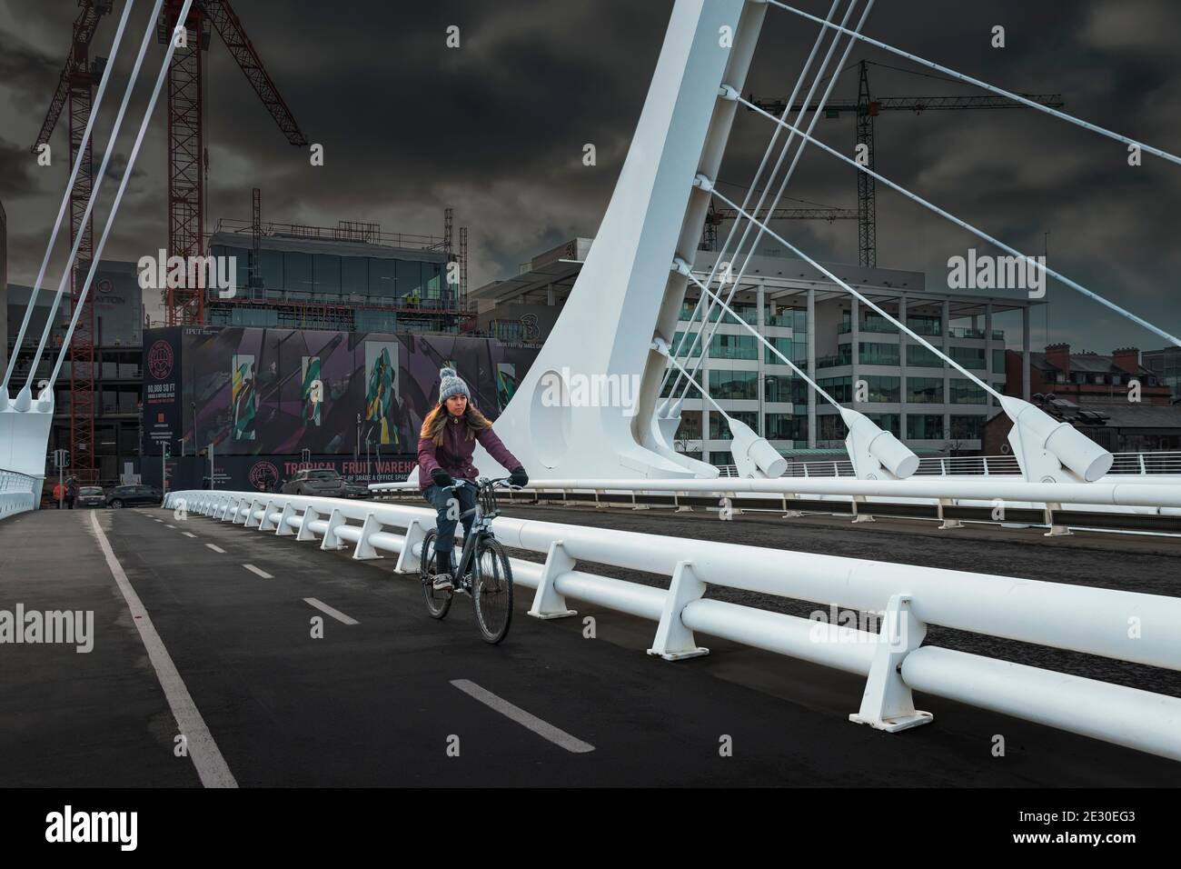Young woman riding bicycle at cycle lane at Harp Bridge (Samuel Beckett ...