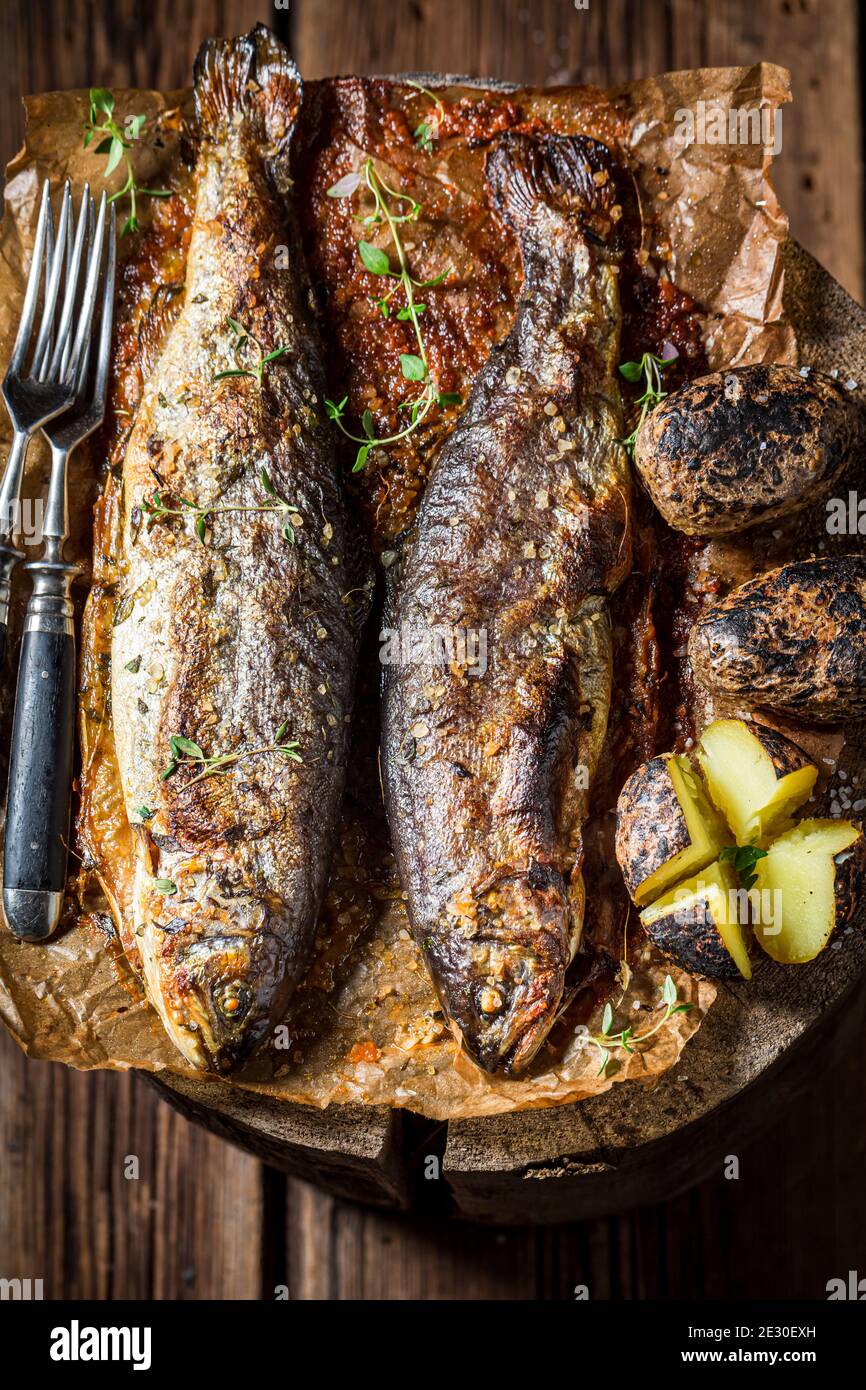 Closeup of trout fish roasted with potatoes and butter on baking paper ...