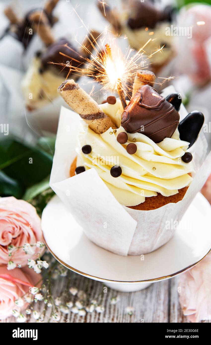 Chocolate cupcakes with burning sparklers on white wooden background ...