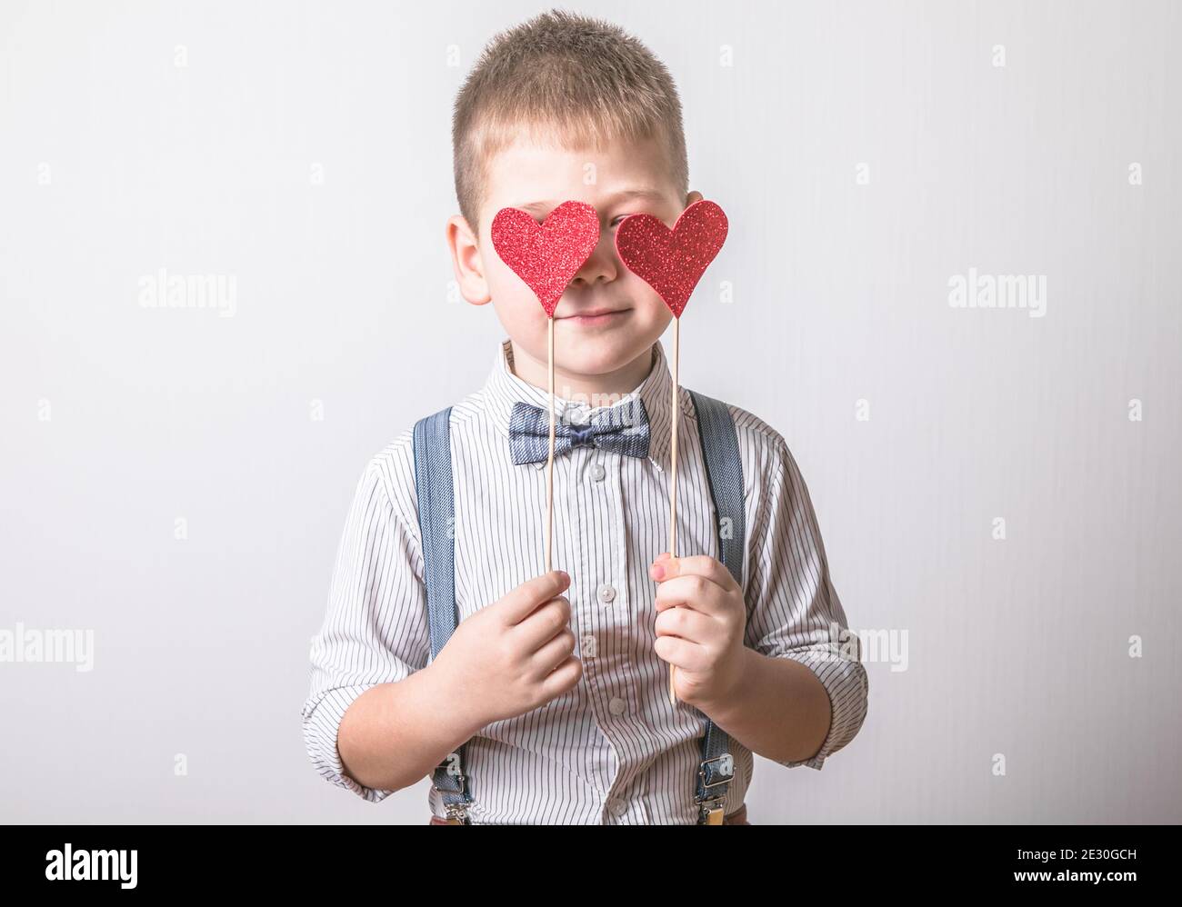 Five year old smiling boy holding a red heart on eays symbol of love ...