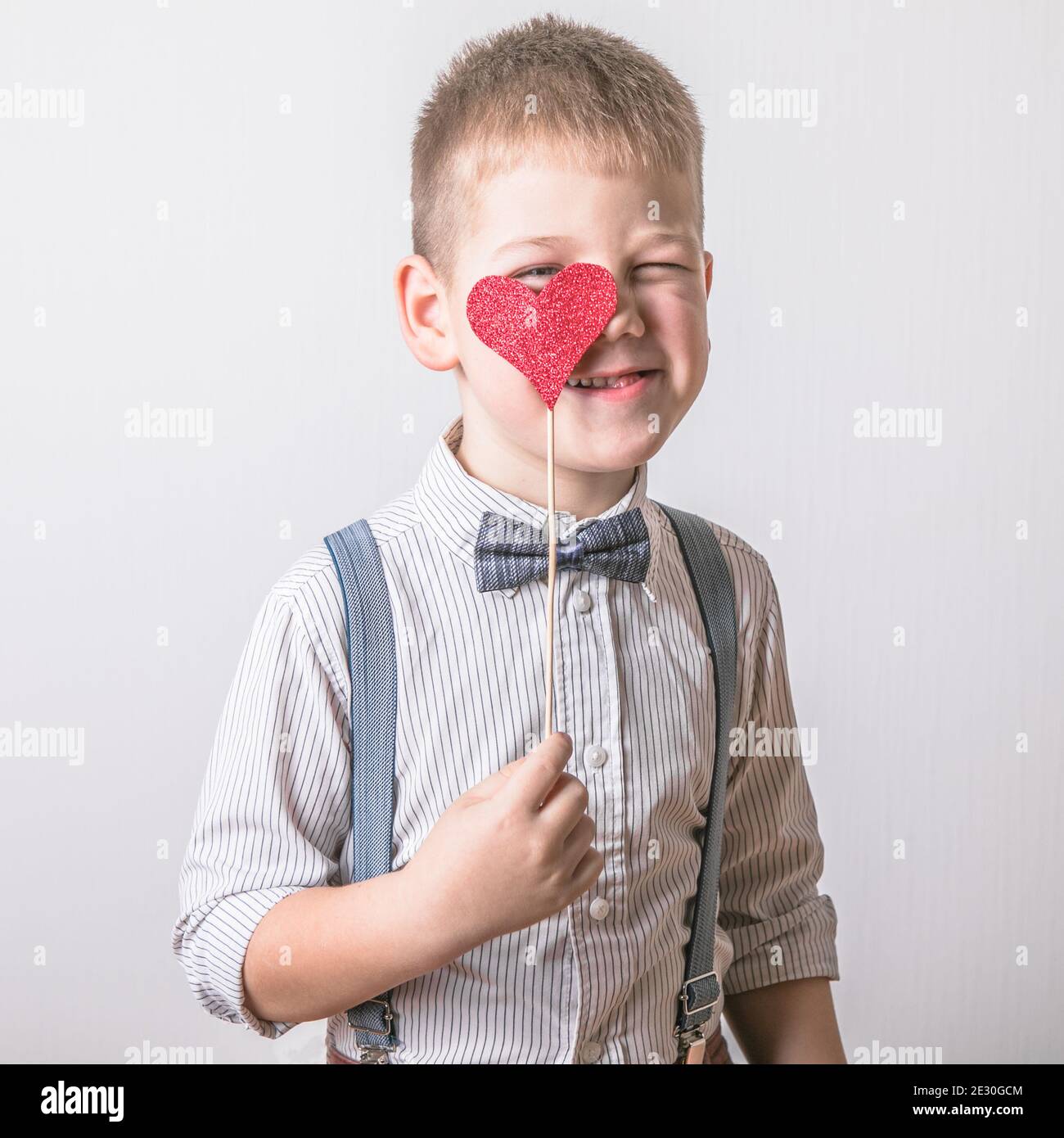 Five year old smiling boy holding a red heart on eays symbol of love ...