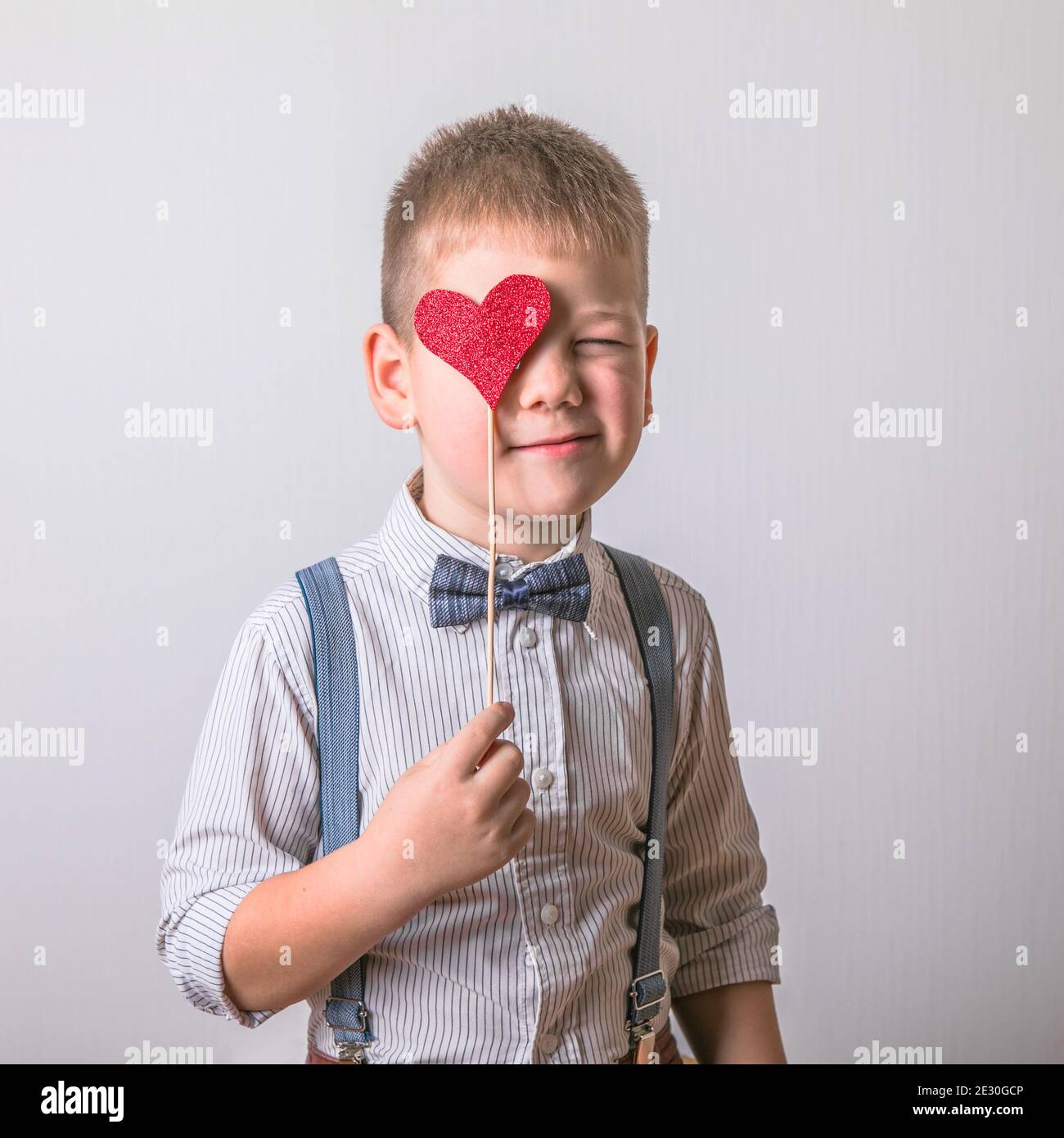 Five year old smiling boy holding a red heart on eays symbol of love ...