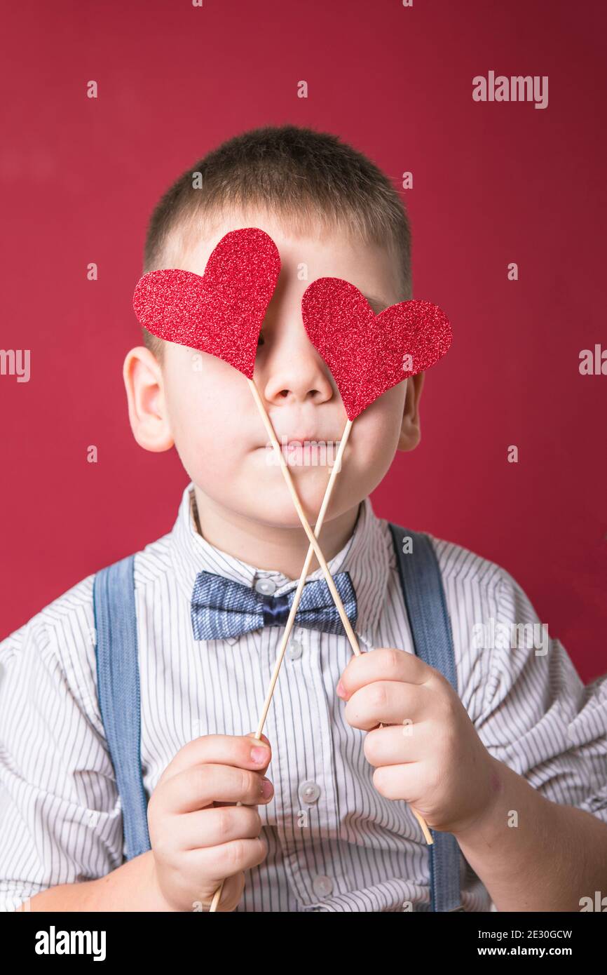 Five year old smiling boy holding a red heart on eays symbol of love ...