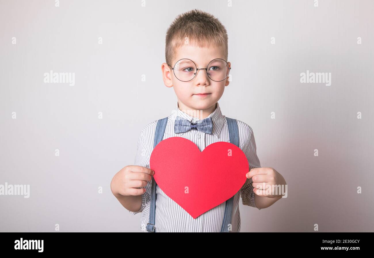 Five year old smiling boy holding a red heart symbol of love, family ...