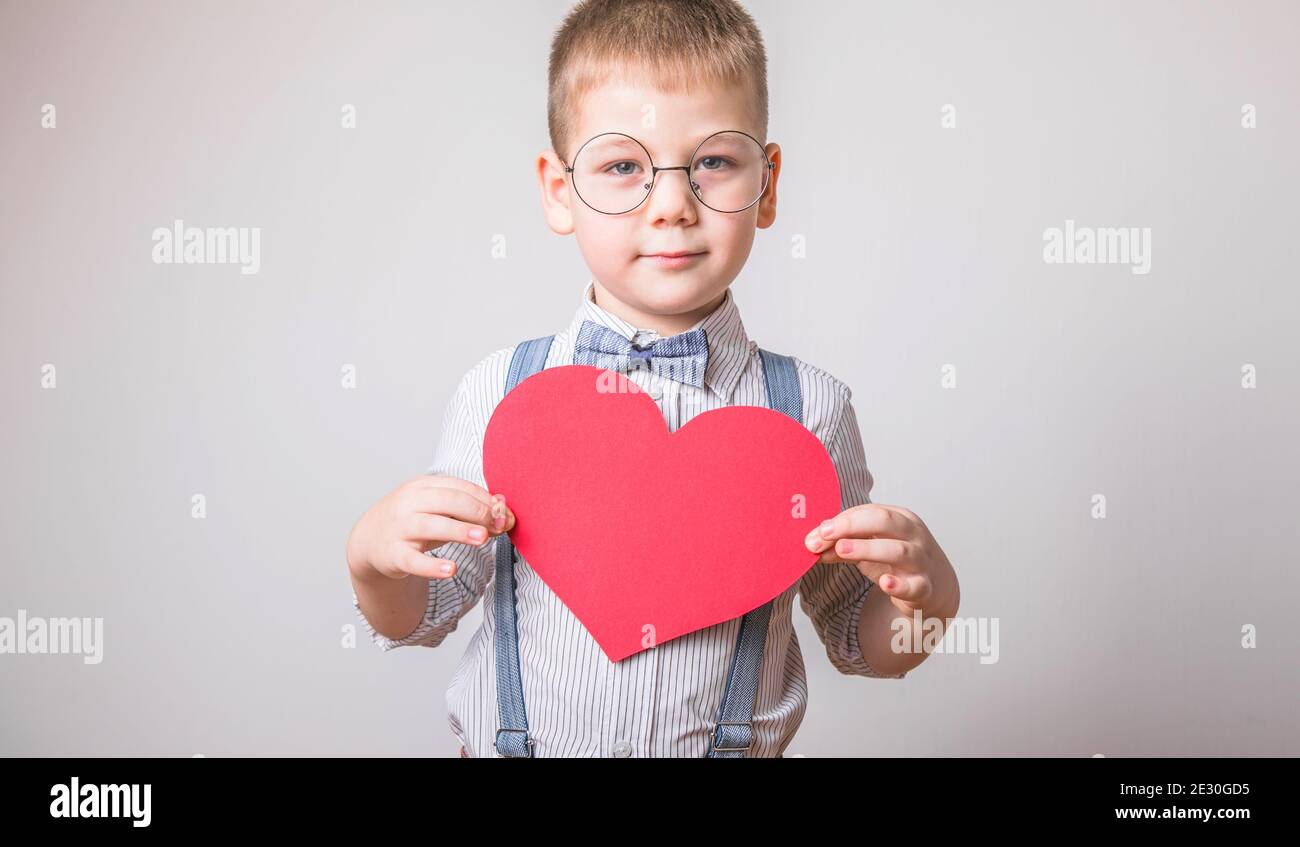 Five year old smiling boy holding a red heart symbol of love, family ...