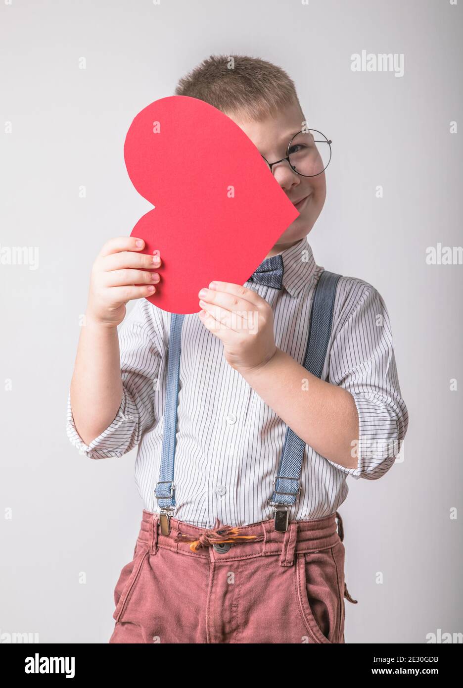 Five year old smiling boy holding a red heart symbol of love, family ...