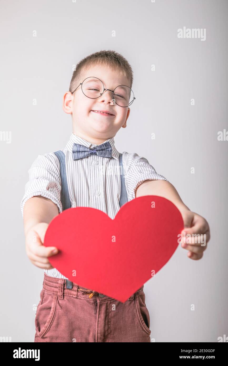 Five year old smiling boy holding a red heart symbol of love, family ...