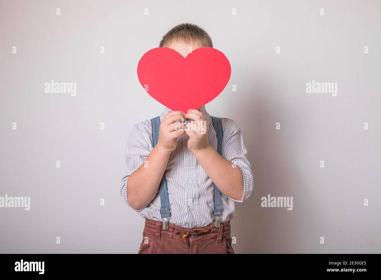 Five year old smiling boy holding a red heart symbol of love, family ...