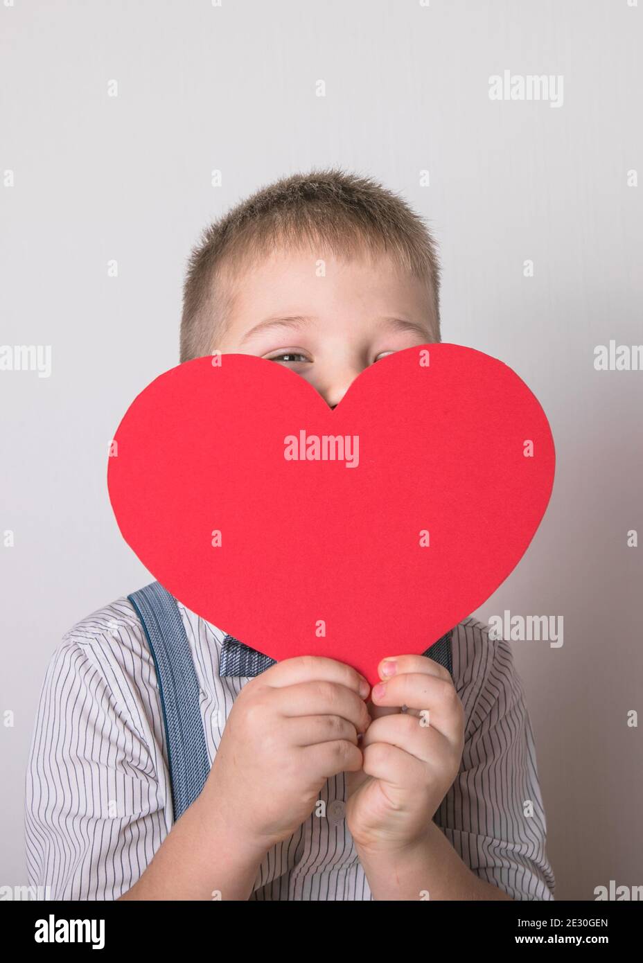 Five year old smiling boy holding a red heart symbol of love, family ...