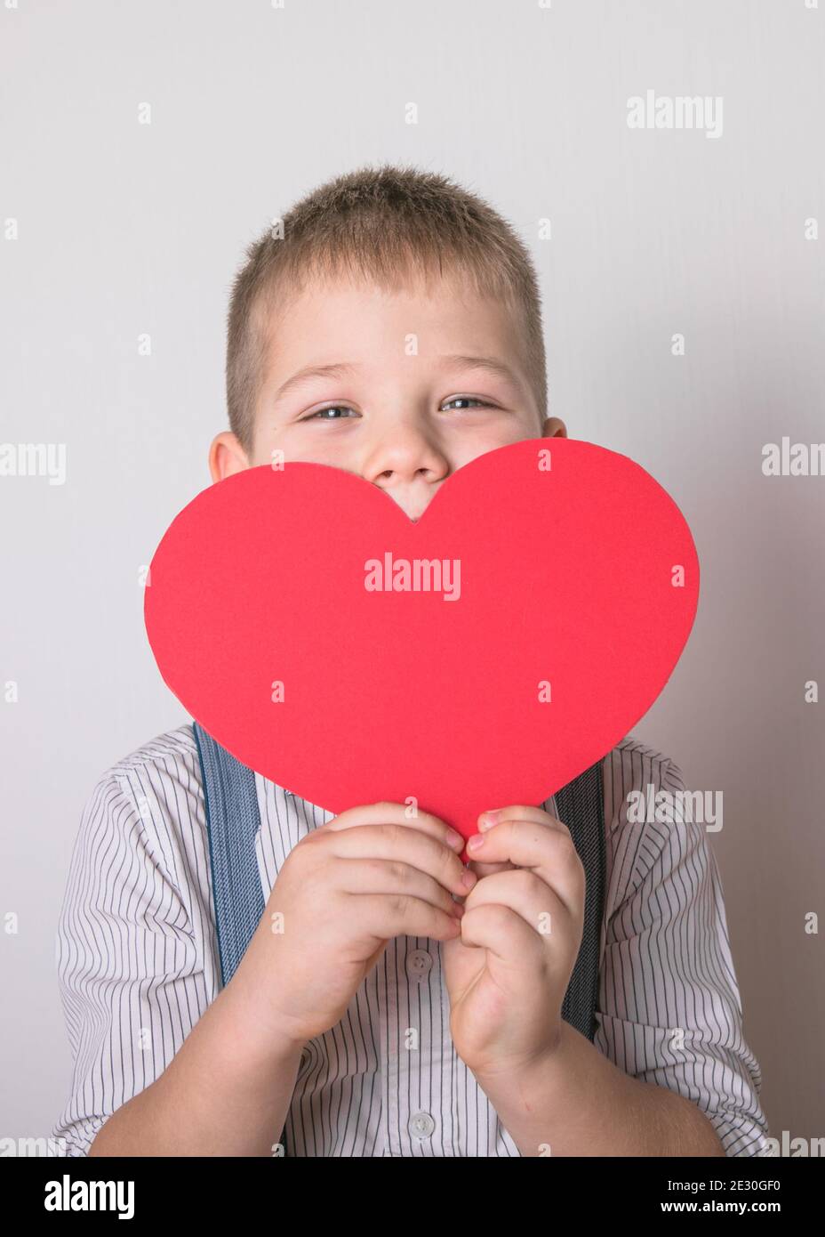 Five year old smiling boy holding a red heart symbol of love, family ...