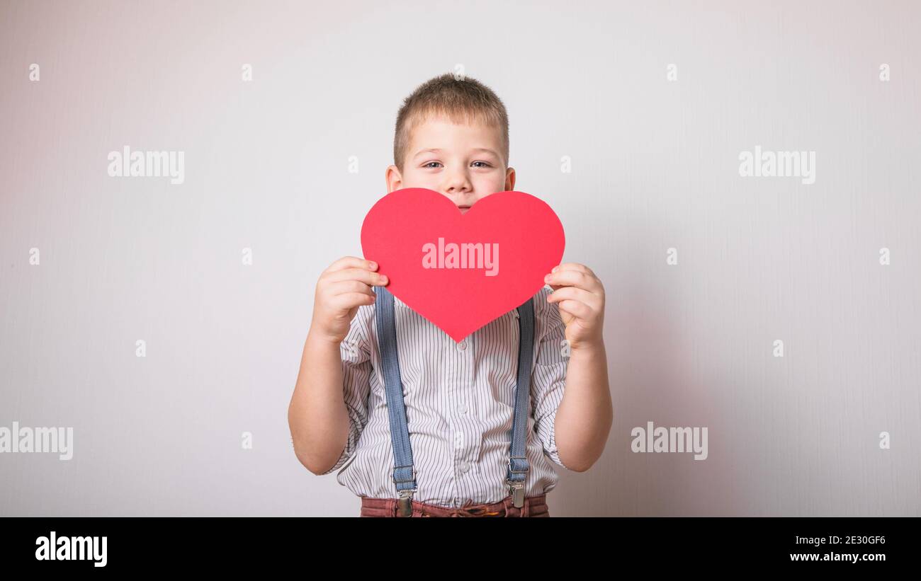 Five year old smiling boy holding a red heart symbol of love, family ...