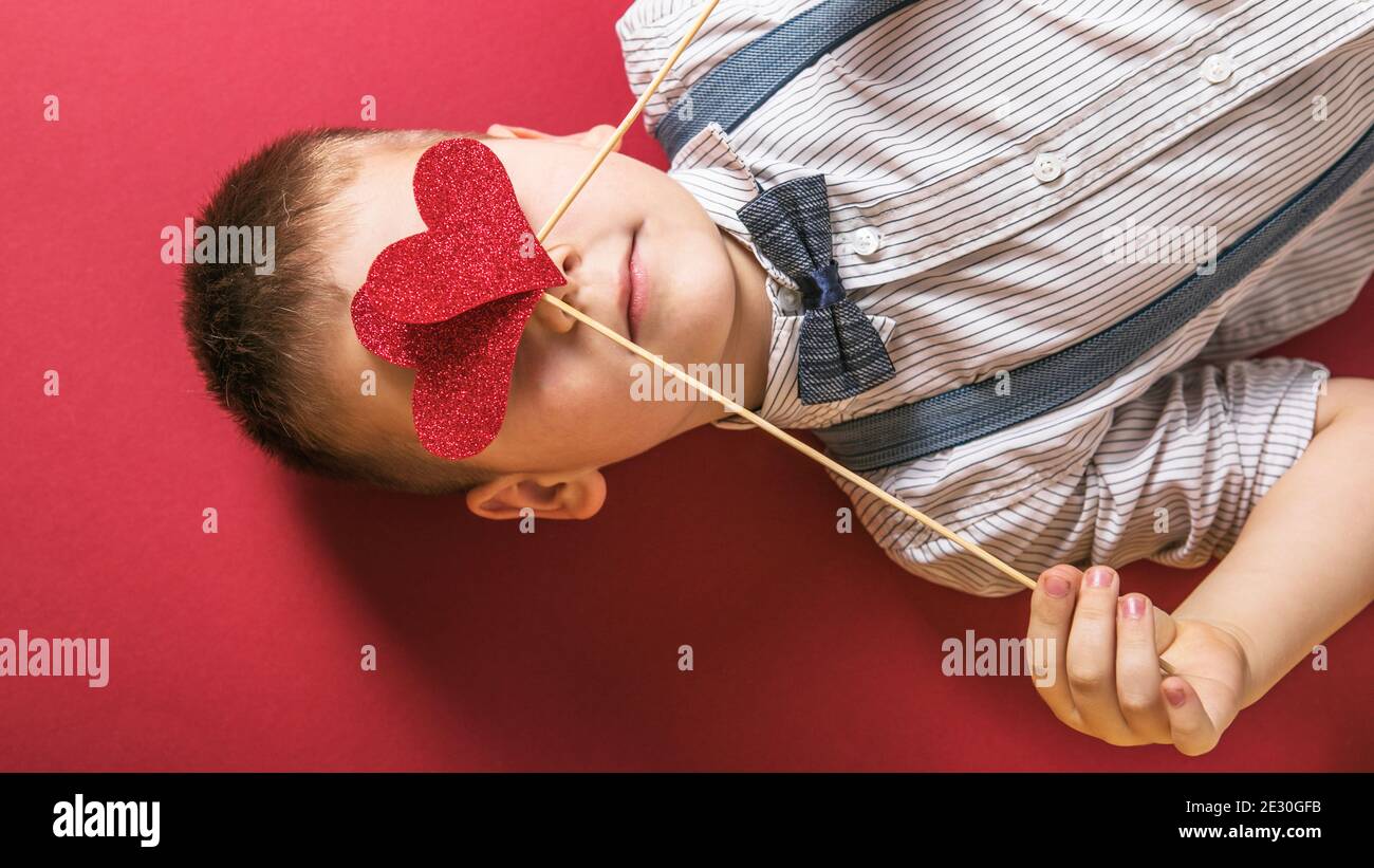 Five year old smiling boy holding a red heart on eays symbol of love ...