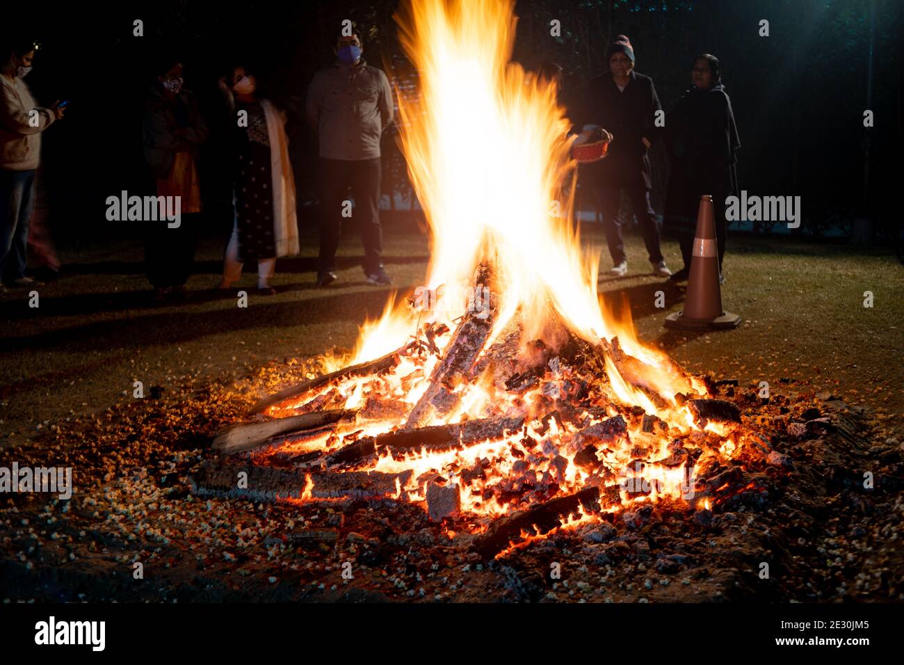 Men women families standing around giant blazing wood fire on lohri ...