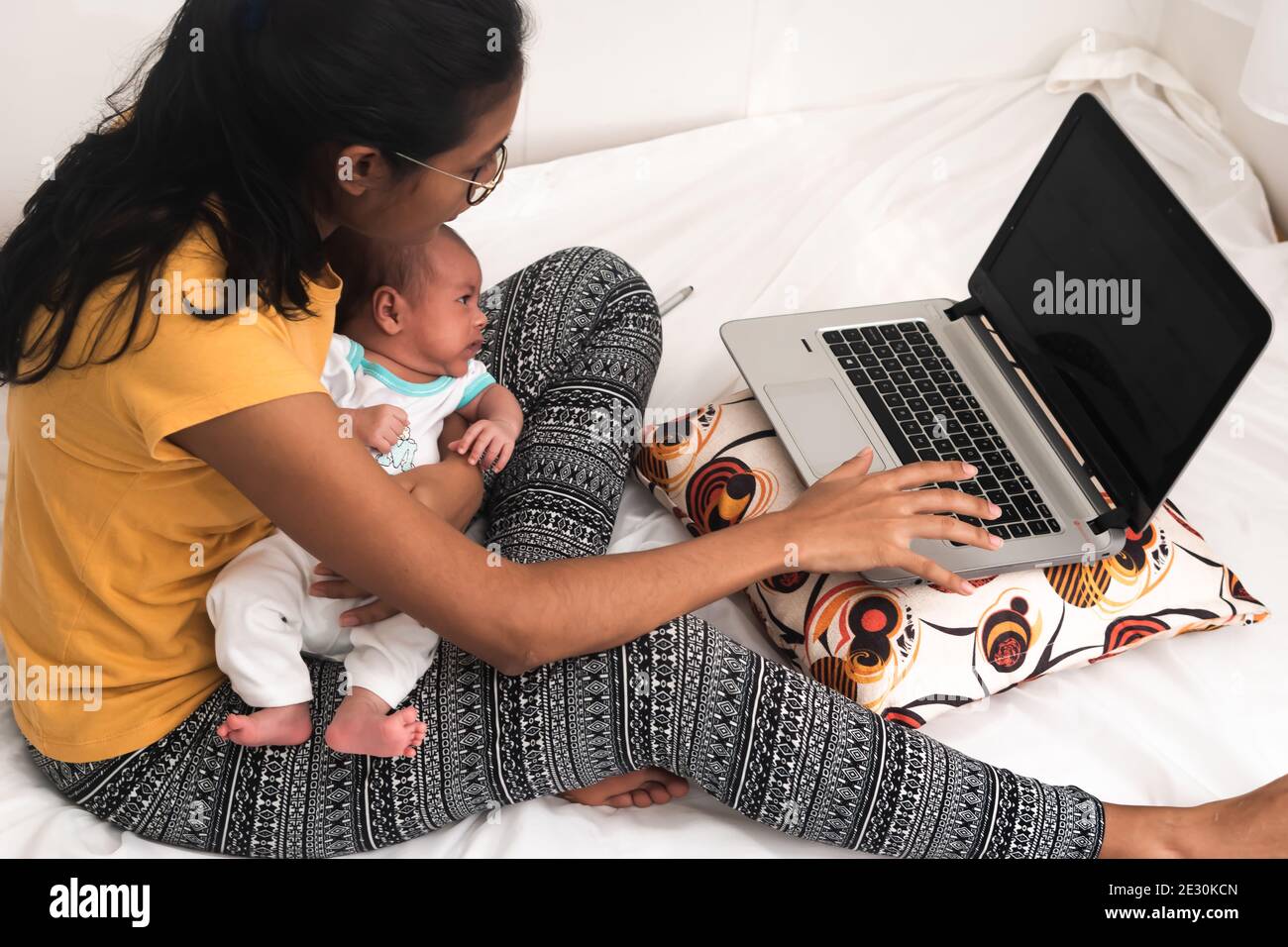 Young Hispanic mother with a baby working from home Stock Photo - Alamy