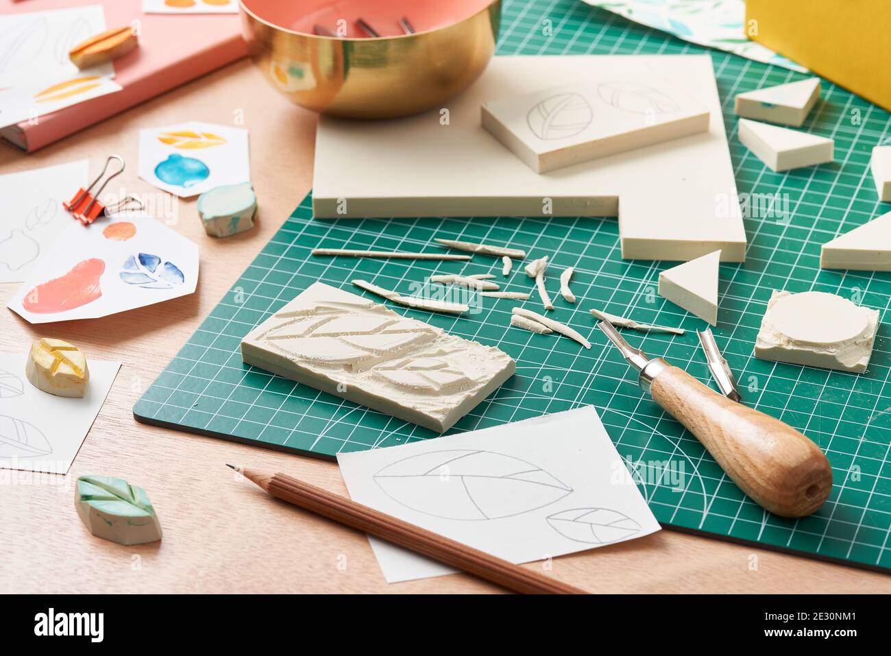 Chisel and pencil placed on desk near pieces of rubber and stamp ...