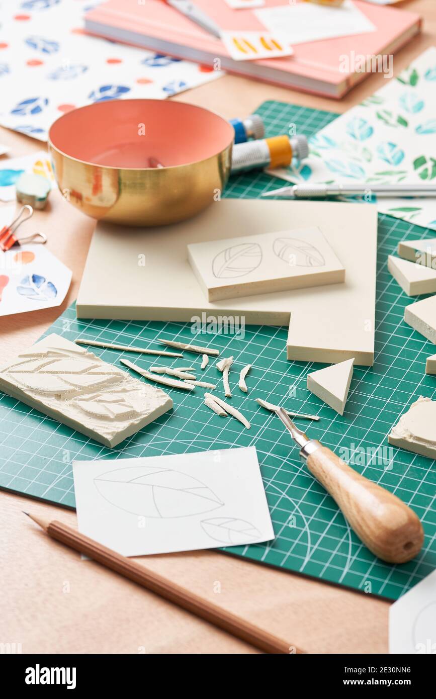 Carved rubber stamps placed on table near bowl and paper sheets with ...