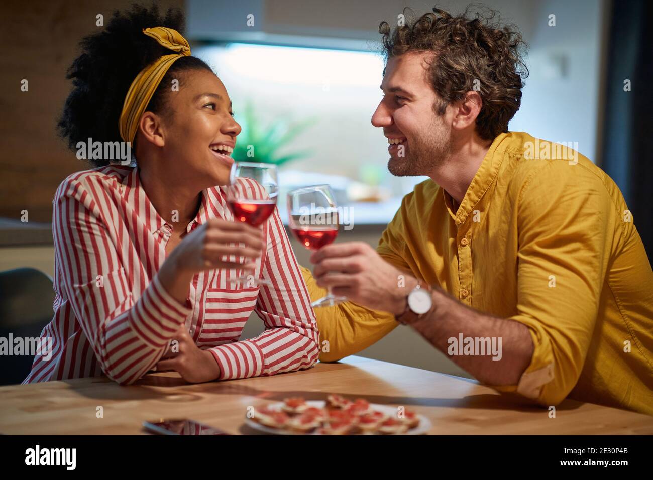 Happy mixed couple relaxing and drinking wine together at home Stock ...